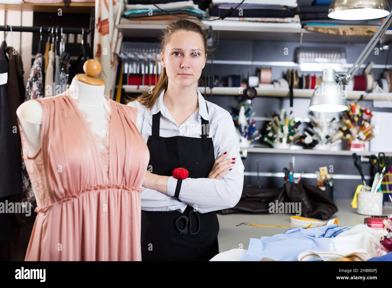 Portrait of female seamstress is who is posing in her design studio ...