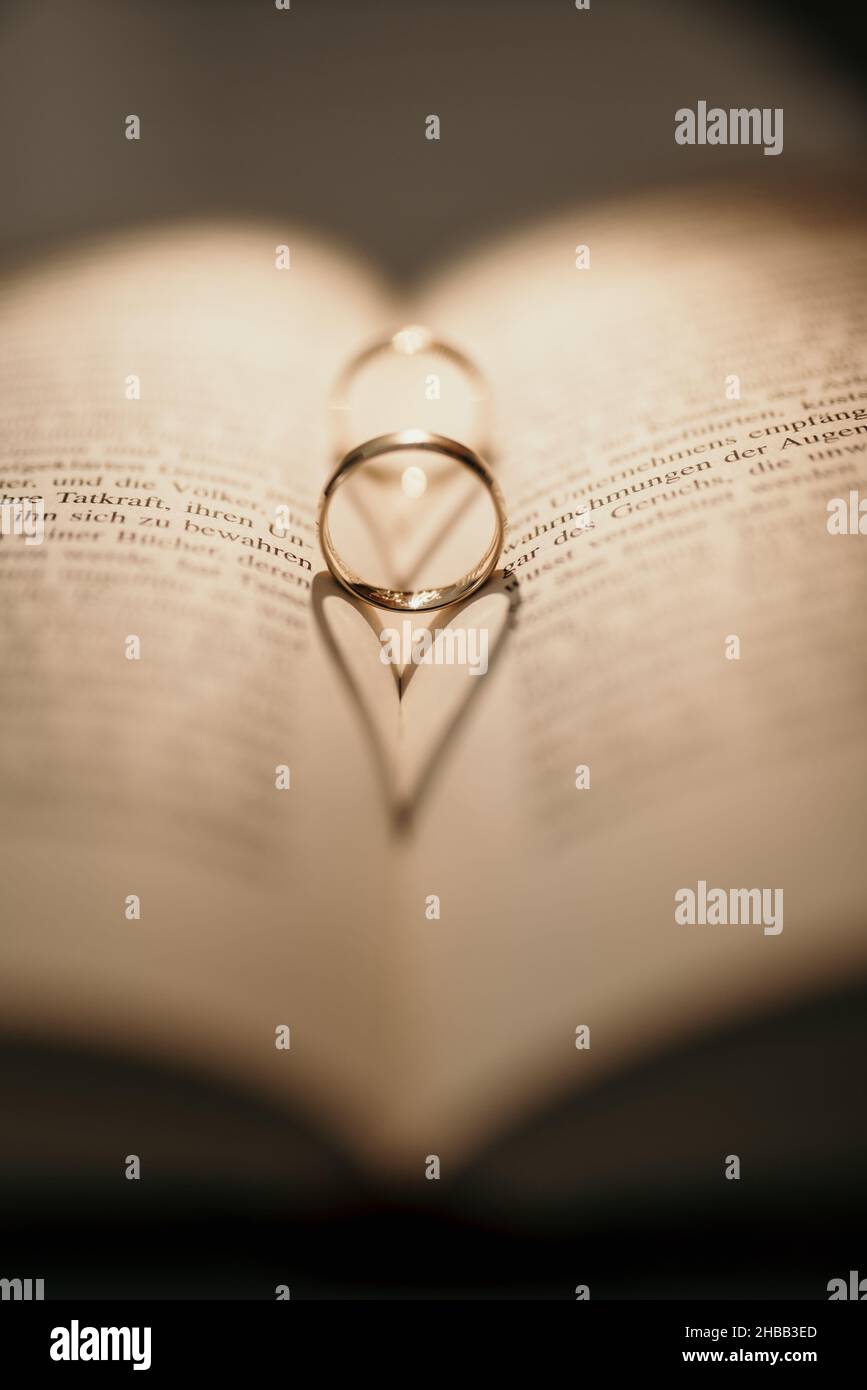 Closeup of engagement rings between book pages creating a heart-shaped ...