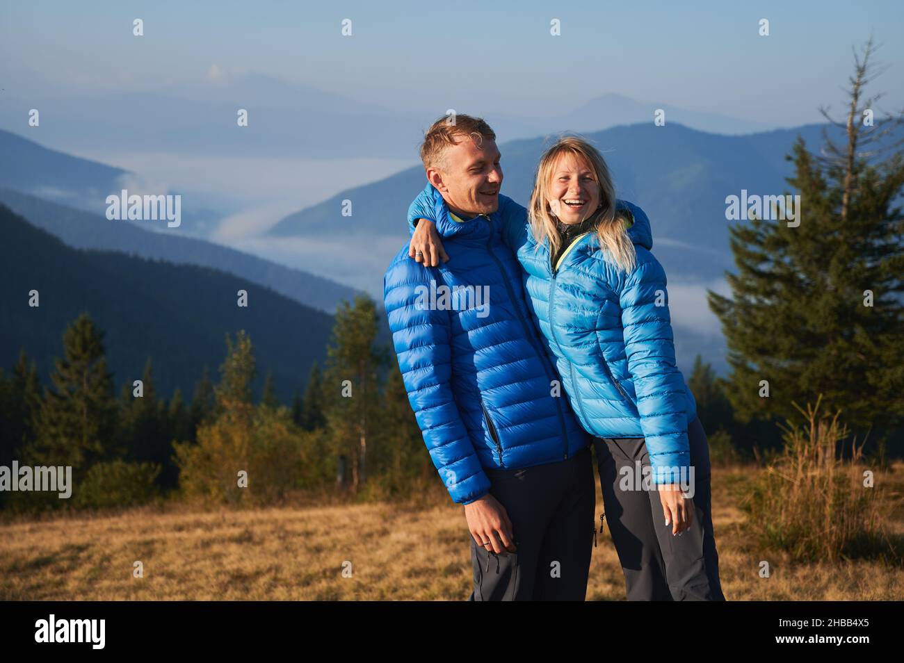Two happy travelers standing and embracing on the background of trees ...