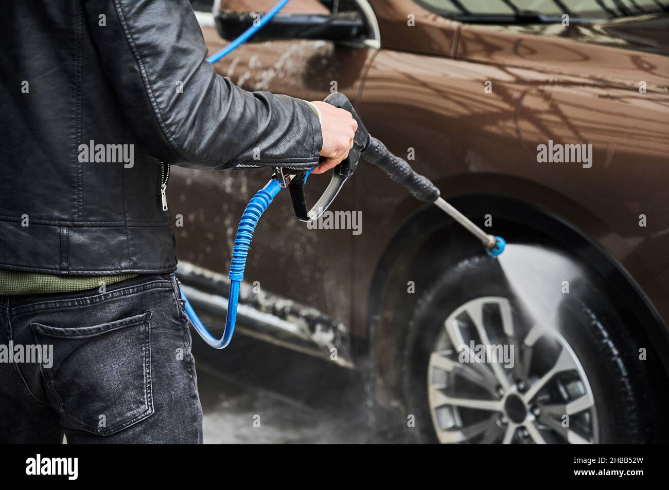 Cropped view of man washing car on carwash station outdoor. Driver ...