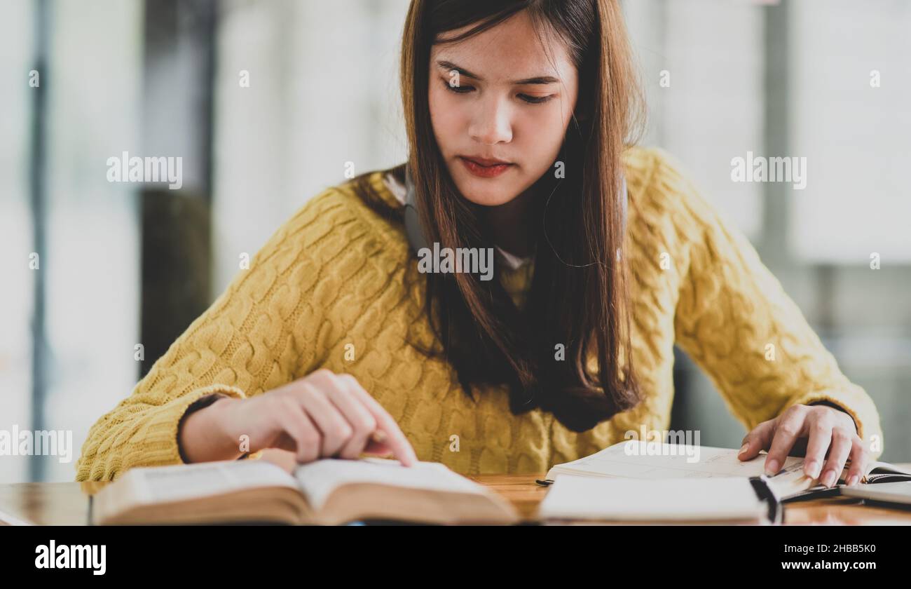 A teenage girl intently reads a book to prepare for an exam Stock Photo ...