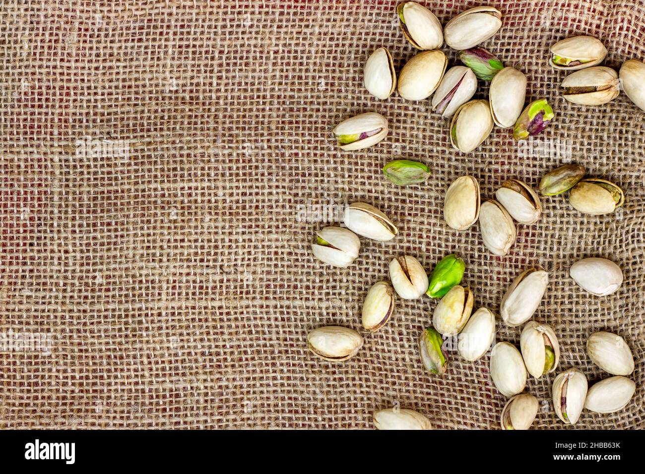 Top view of roasted salted pistachio nuts in nutshell with copy space for text on textile ...