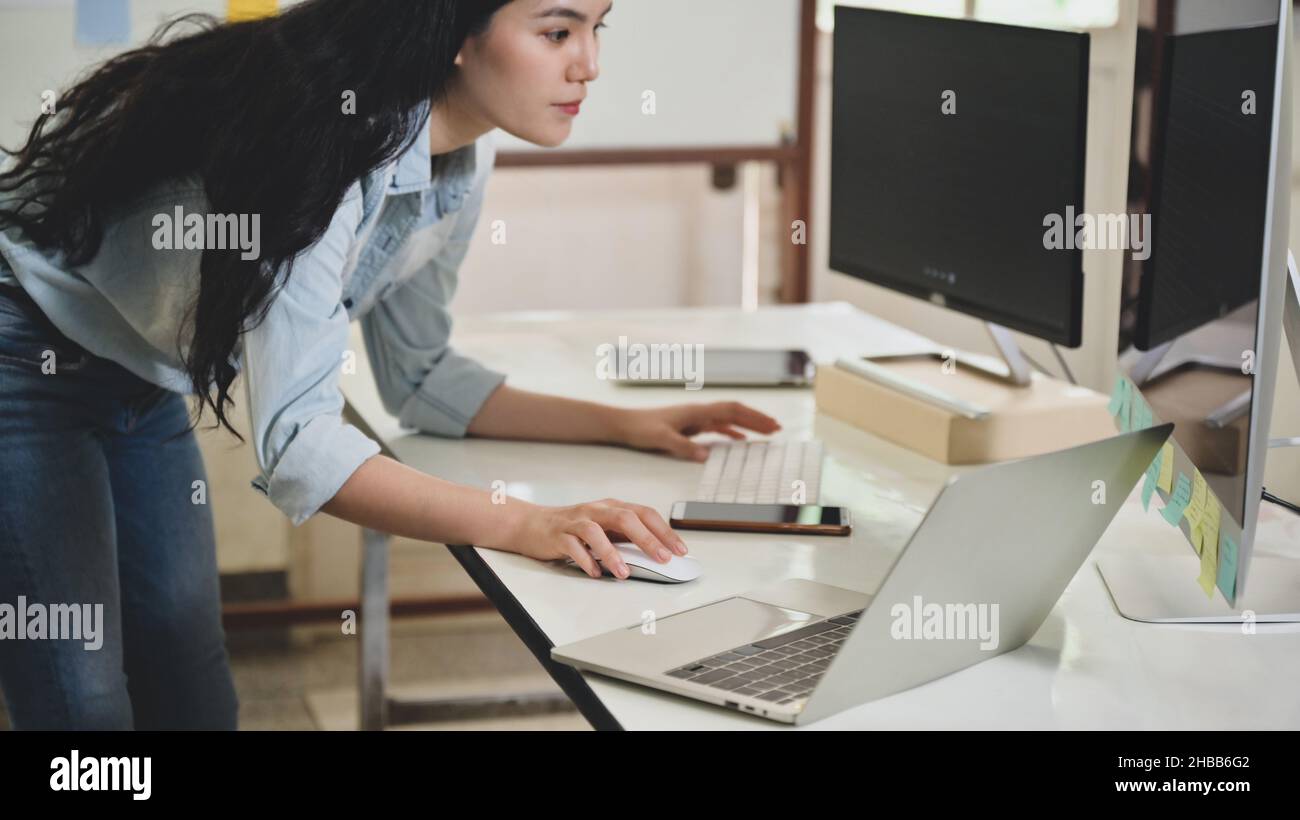 A female programmer bends down to use a computer to review a client ...