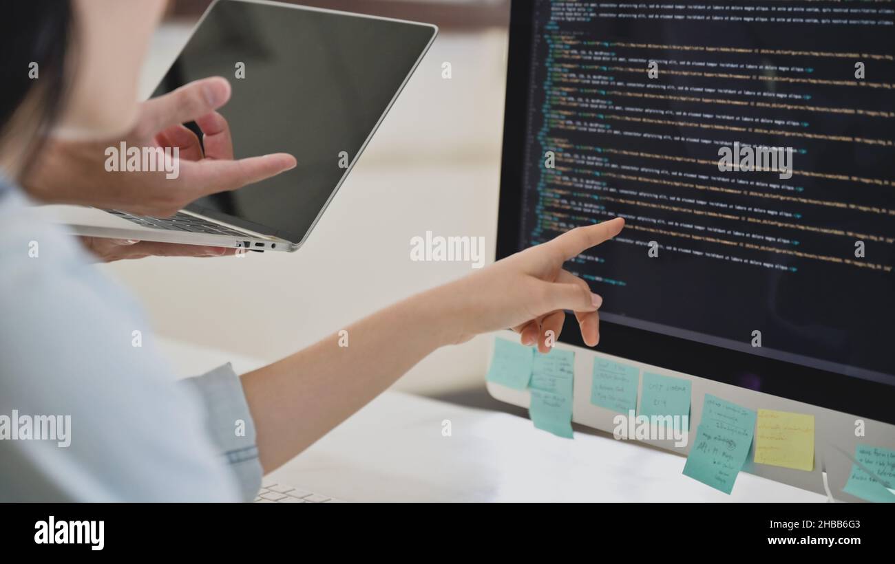 A team of programmers are checking the code on the computer screen ...