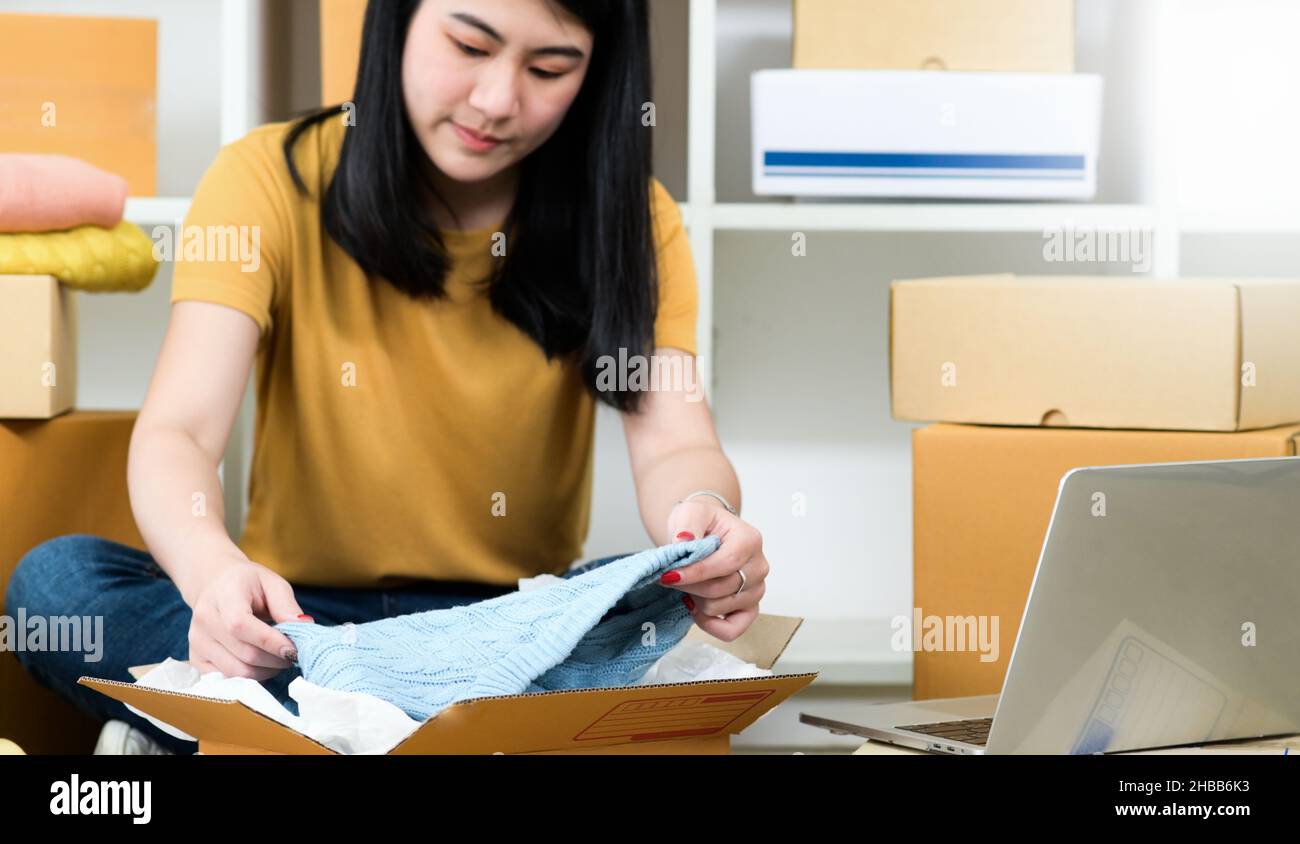 Woman packs a shirt in a parcel box for delivery to a customer,Sell ...