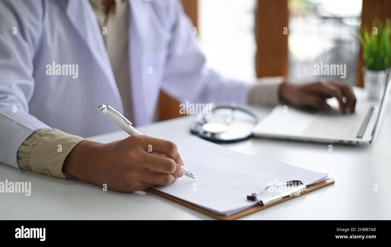 Medical concepts, Doctor wearing a lab gown recording the results of ...