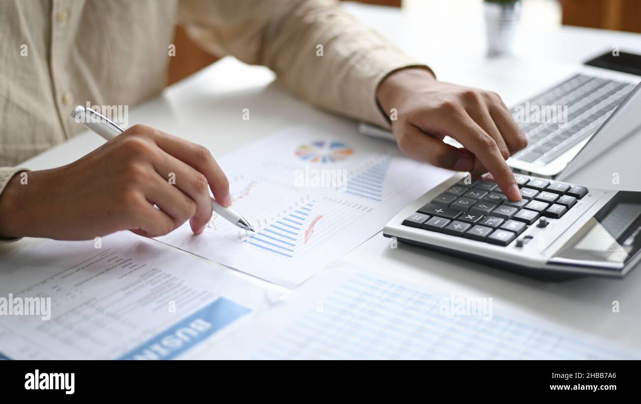 Close-up shot of Hand pointing pen to graph data and using calculator ...