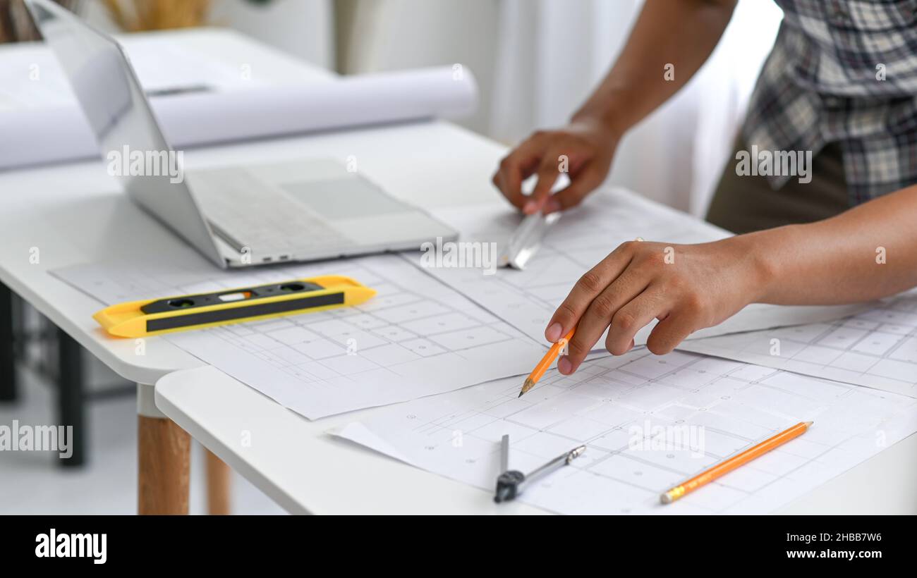The architect's hand held a pencil and a ruler examining the house plan ...
