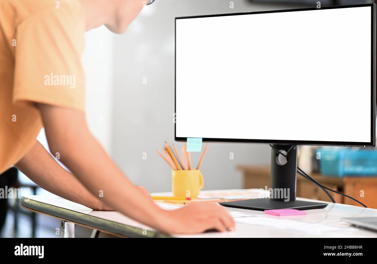 Young man operating a mockup computer big blank screen, using a ...
