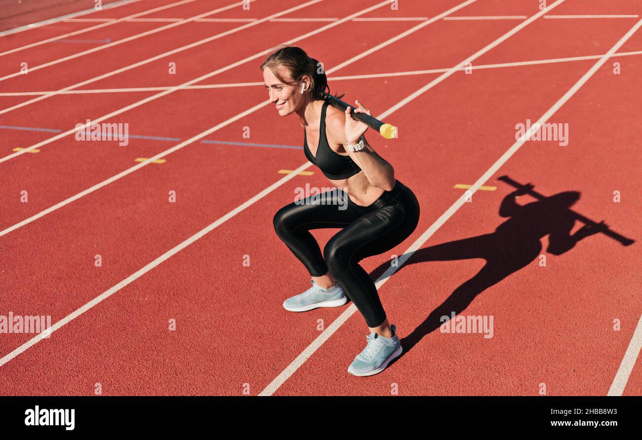 Young athletic woman in sportswear doing squats exercise with gymnastic ...
