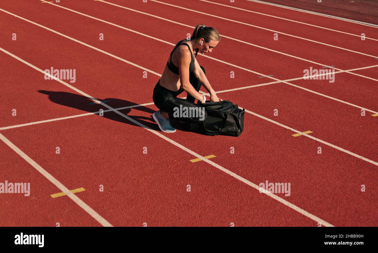 Young woman athlete in sportwear getting ready for workout and opening ...