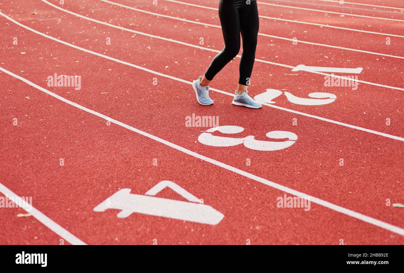 Young runner woman in sportwear run on stadium red track with numbers ...