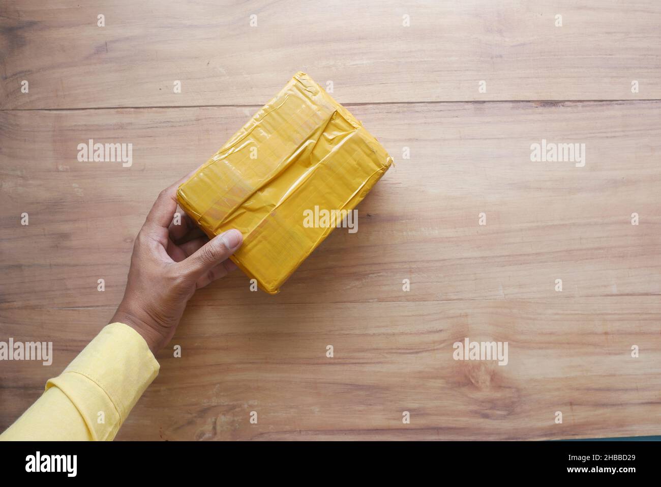 hand holding a yellow color deliver packet on table Stock Photo - Alamy