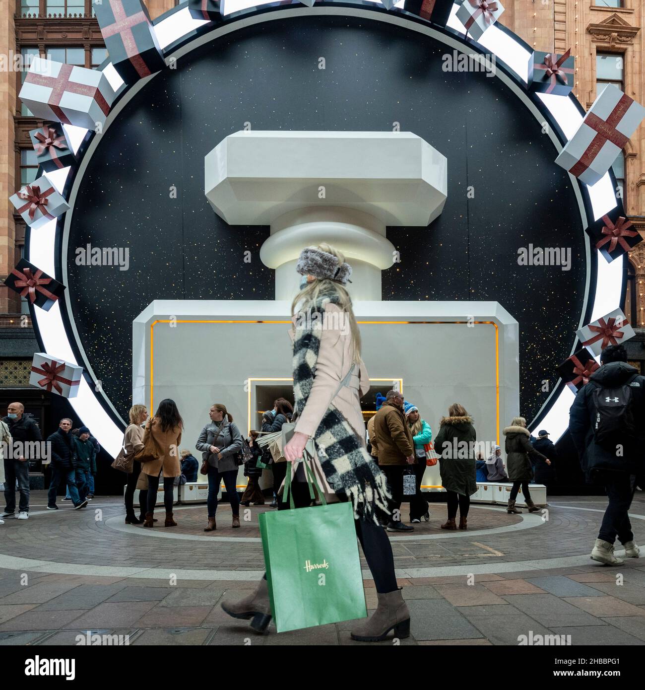 London, UK. 18 December 2021. A shopper with a green Harrods bag ...