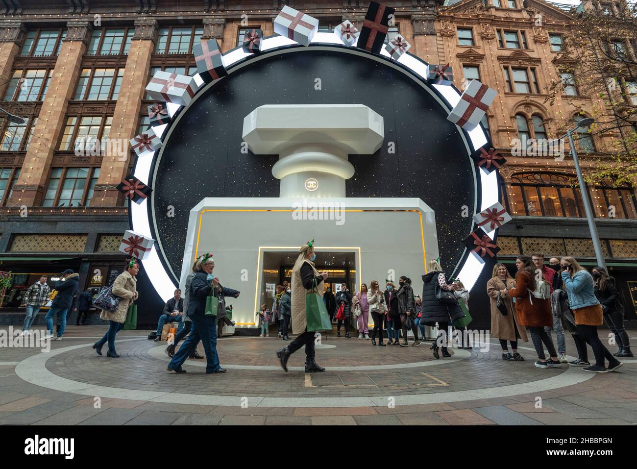 London, UK. 18 December 2021. Shoppers with green Harrods bags outside ...