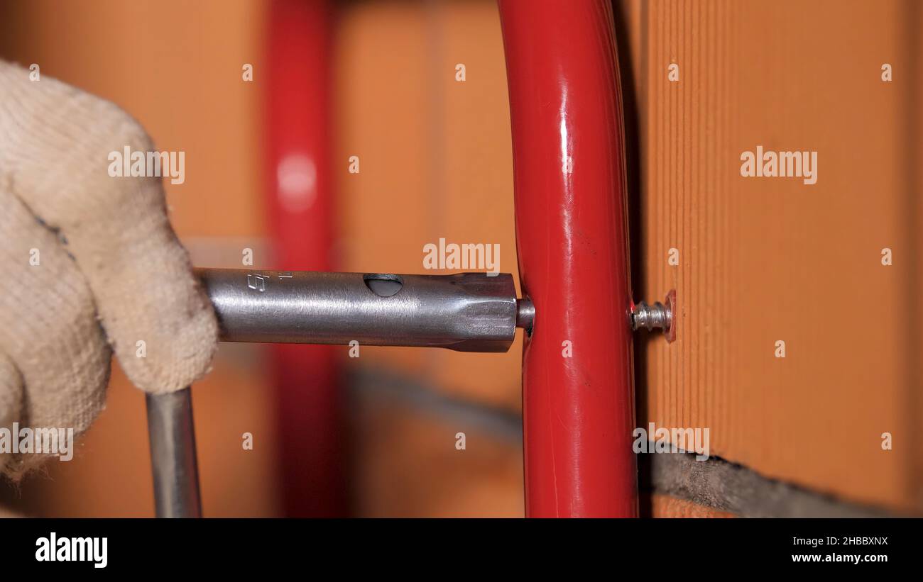 Side view of a man tightening the screw inside the red ceramic blocks ...