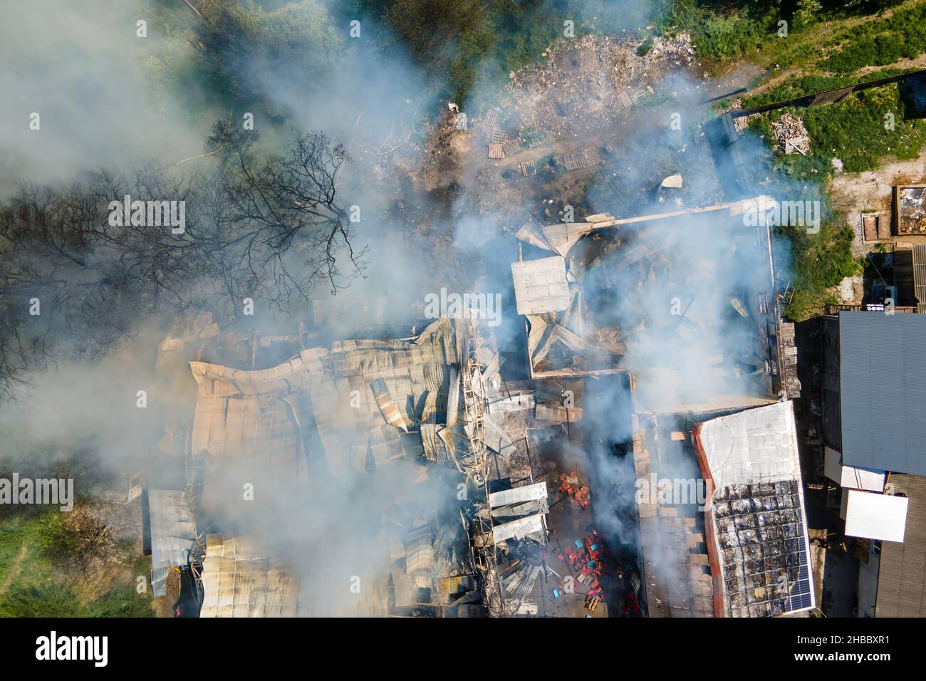 Aerial view of ruined building on fire with collapsed roof and rising ...