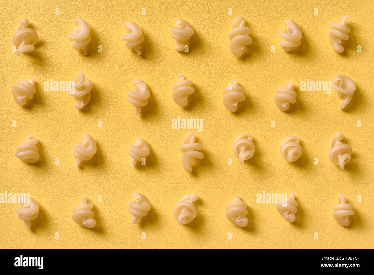 Rows of whole raw funghetto pasta flat on a yellow background Stock ...