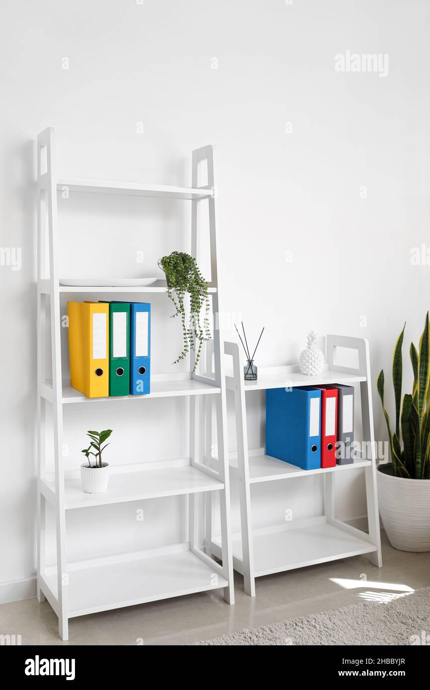 Shelving units with folders near light wall Stock Photo - Alamy