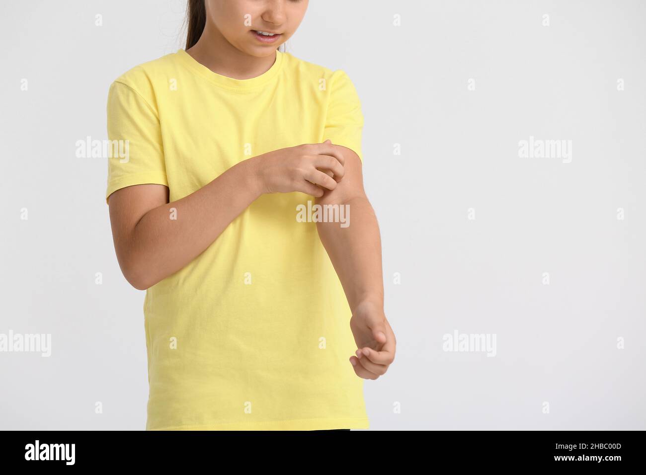 Little girl scratching herself on light background Stock Photo - Alamy