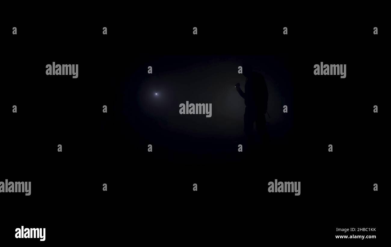 Man exploring huge underground cave with dim torch, adventure and ...