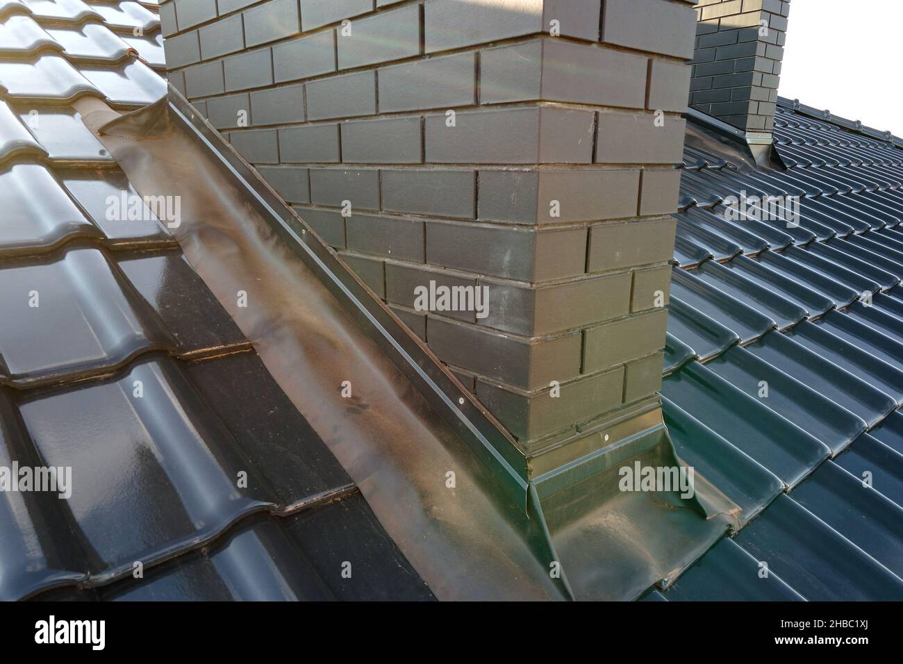 Closeup of brick chimney on house roof top covered with ceramic ...