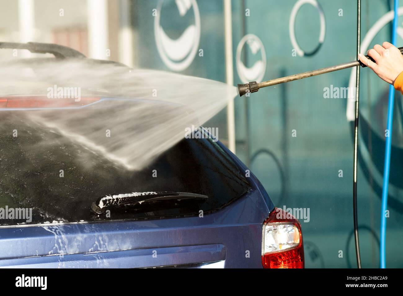 Closeup of male driver washing his car with contactless high pressure ...