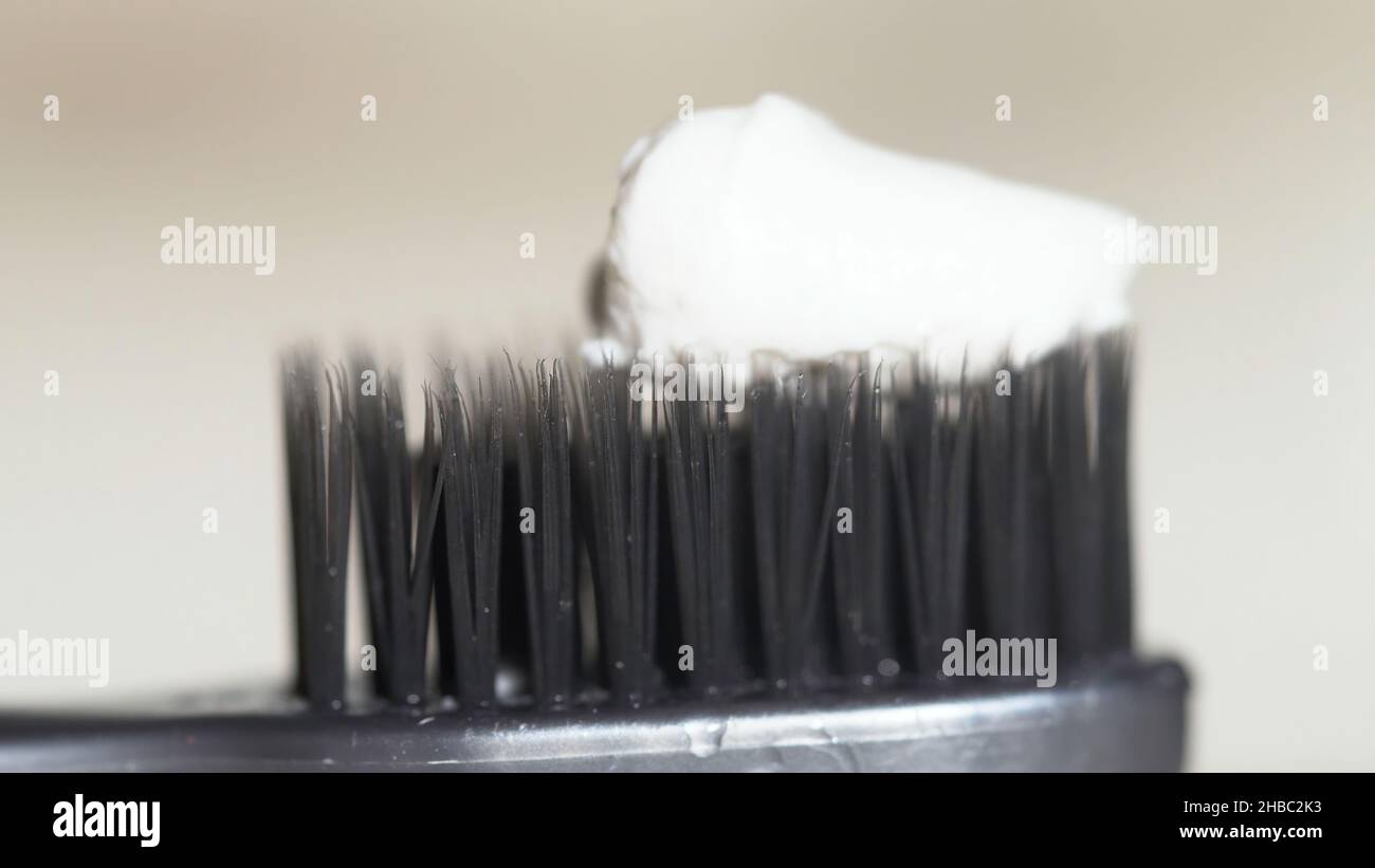Extreme close up for a black toothbrush with white toothpaste being ...