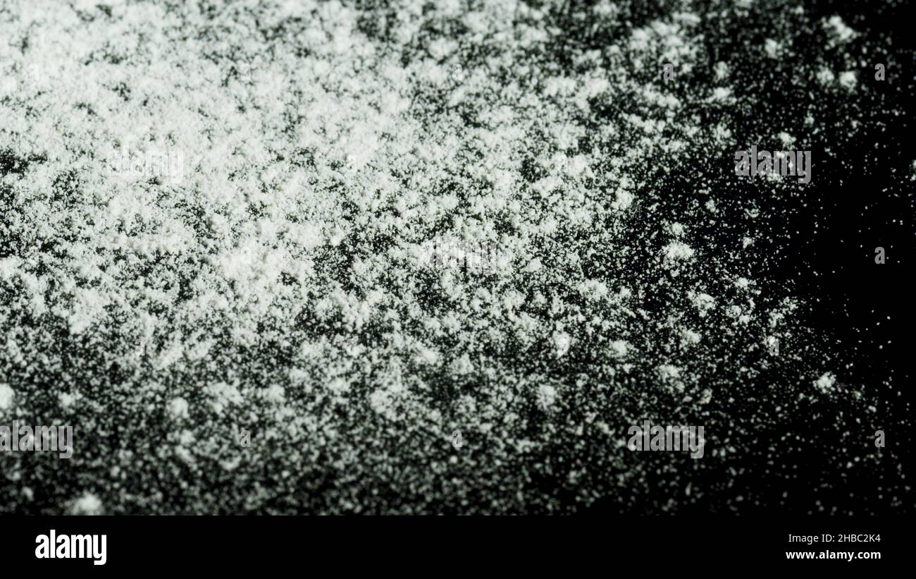 White powder falling down isolated on black background. White dry inks ...