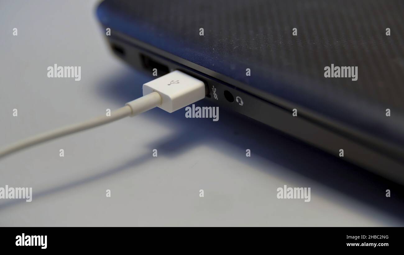 Hand inserting white USB cable into laptop isolated on white background ...