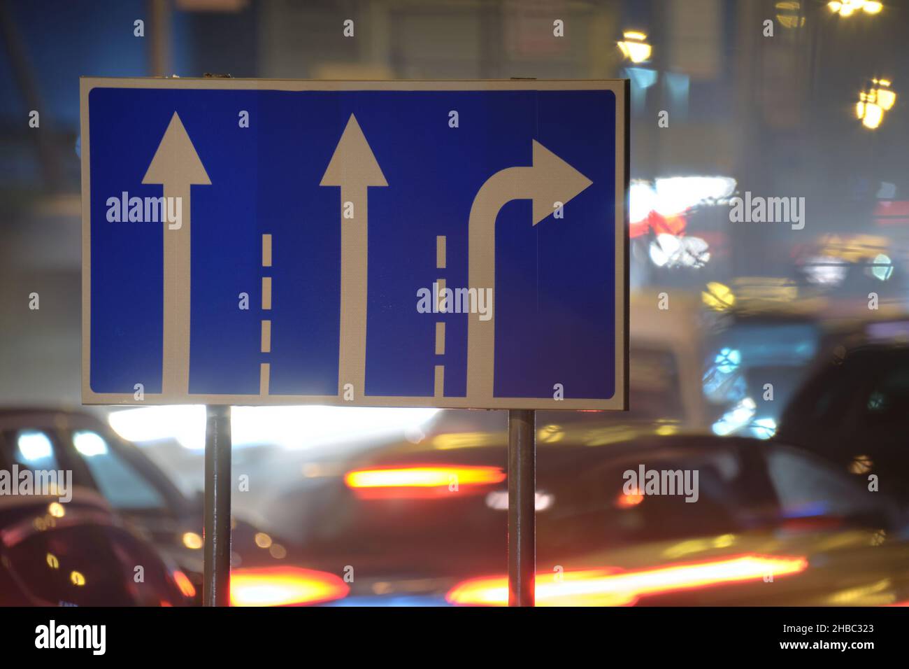 Direction road signs with blurred cars on city street traffic at night ...