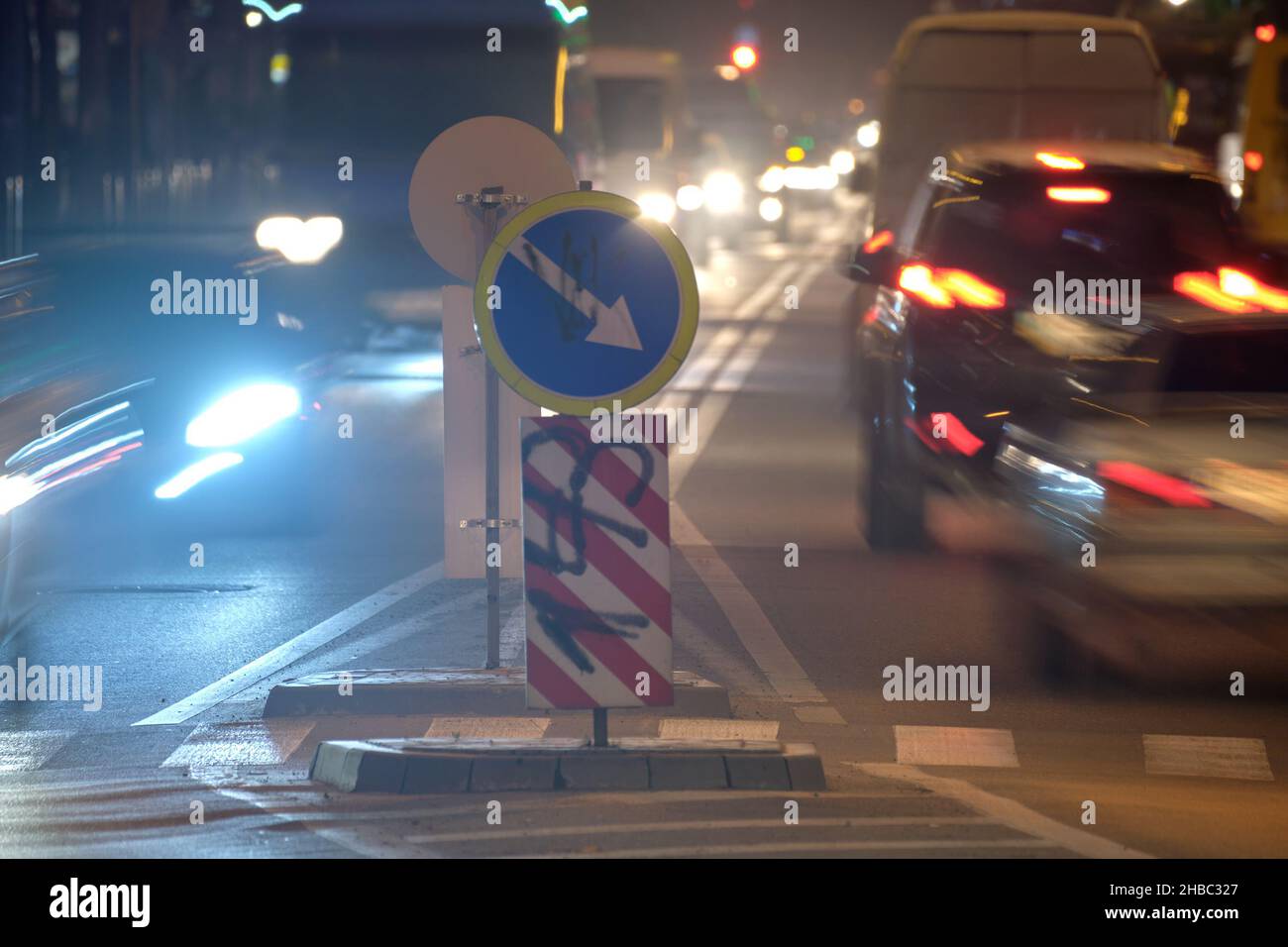 Direction road signs with blurred cars on city street traffic at night ...