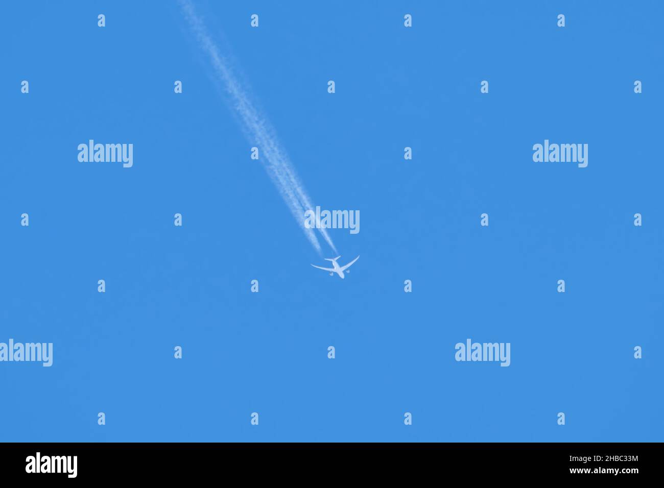 Distant passenger jet plane flying on high altitude on clear blue sky ...