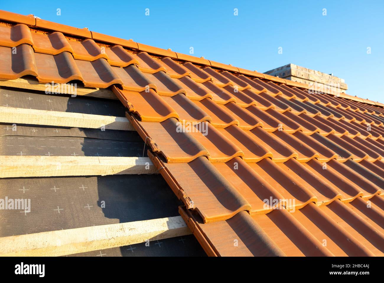 Overlapping rows of yellow ceramic roofing tiles mounted on wooden ...