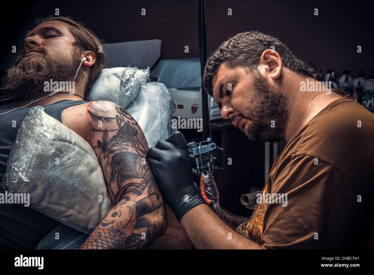 Tattooer makes tattoo in tattoo studio Stock Photo - Alamy