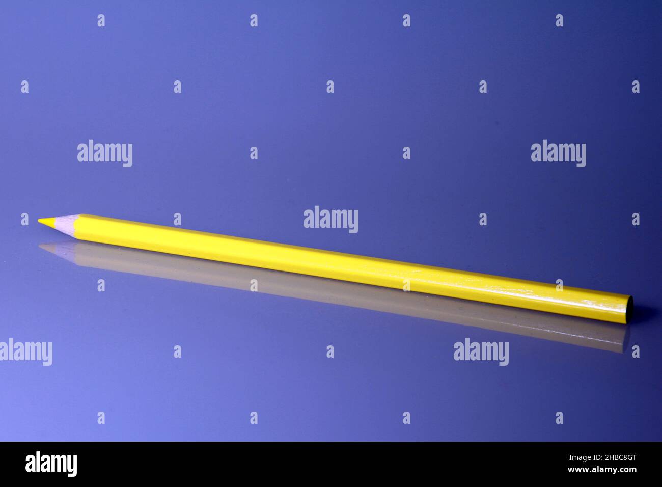 Close-up shot of a yellow colored pencil for drawing isolated on a blue ...