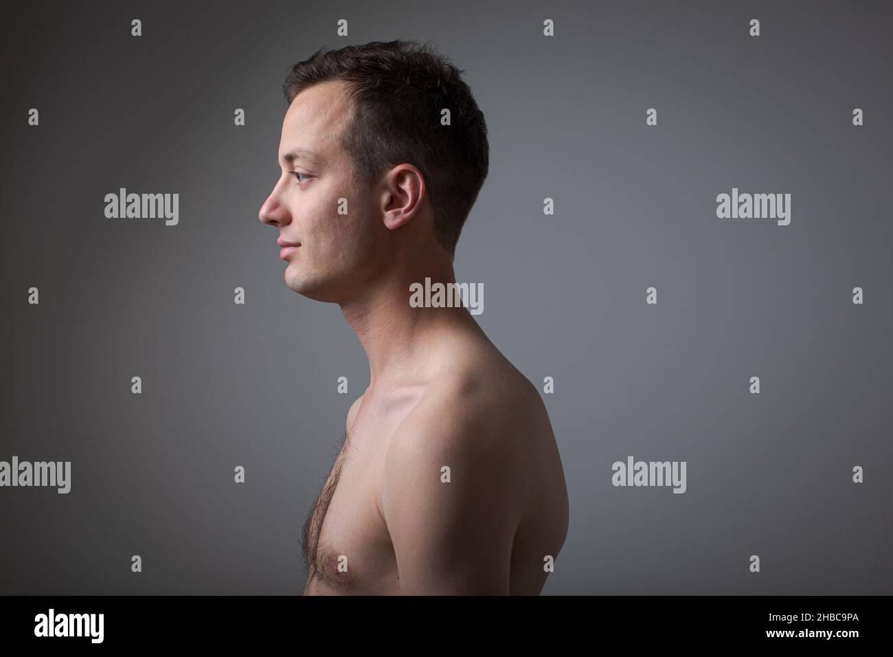 Dark (low key) portrait of a, handsome young man on grey background ...