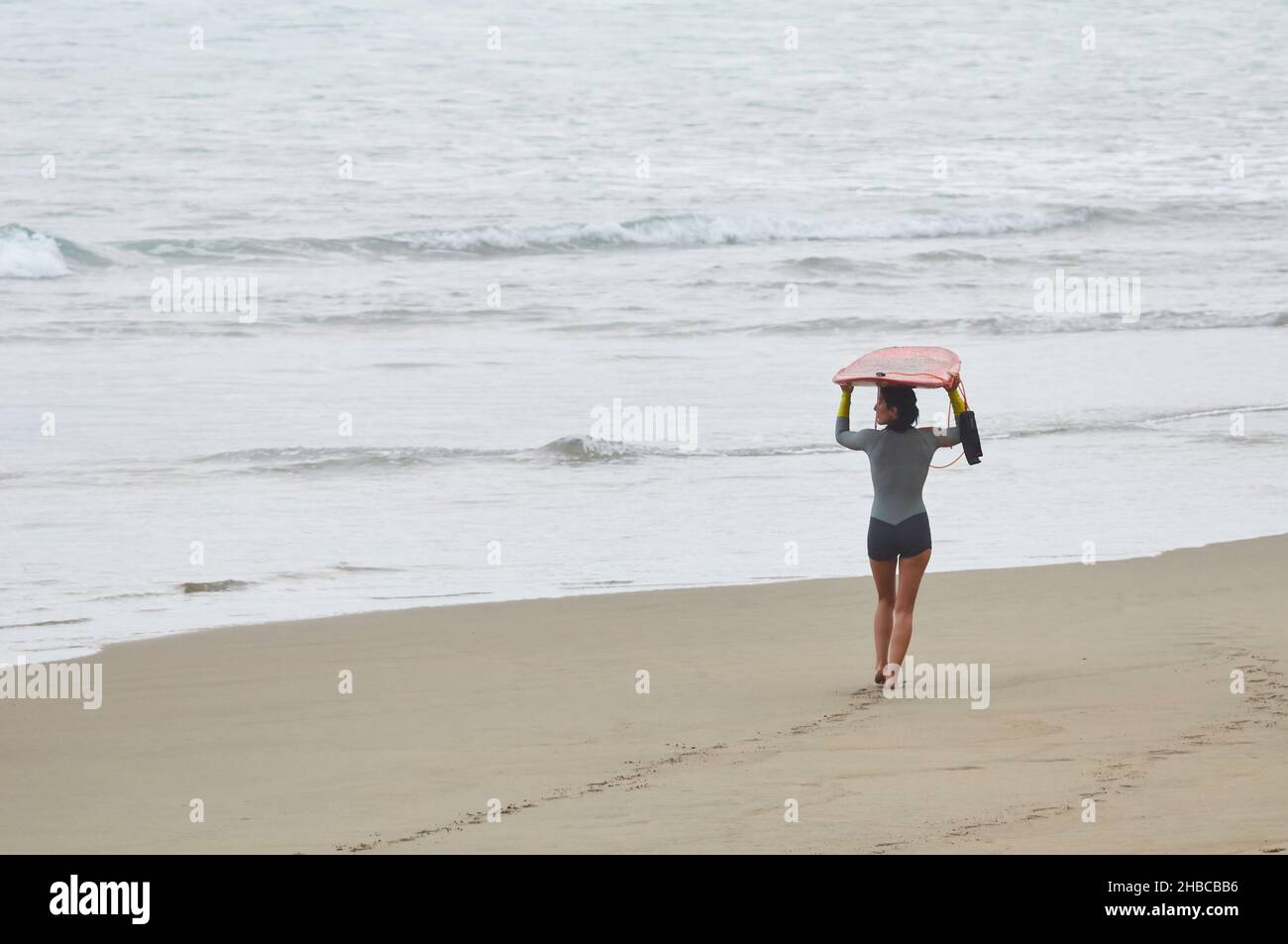 Female surfer with a longboard on her head at the seashore at the XIII ...