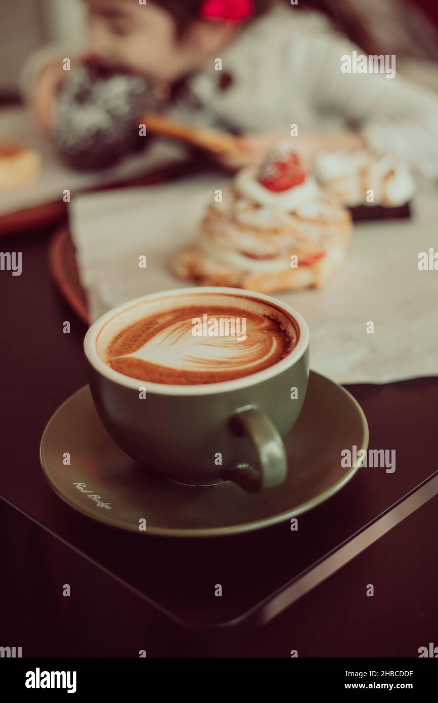 Close-up shot of a cup of fresh cappuccino with heart foam and a sweet ...