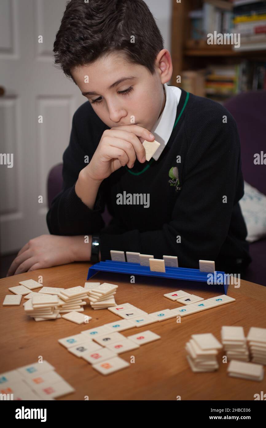 A boy playing Rummikub and thinking about his next play Stock Photo - Alamy