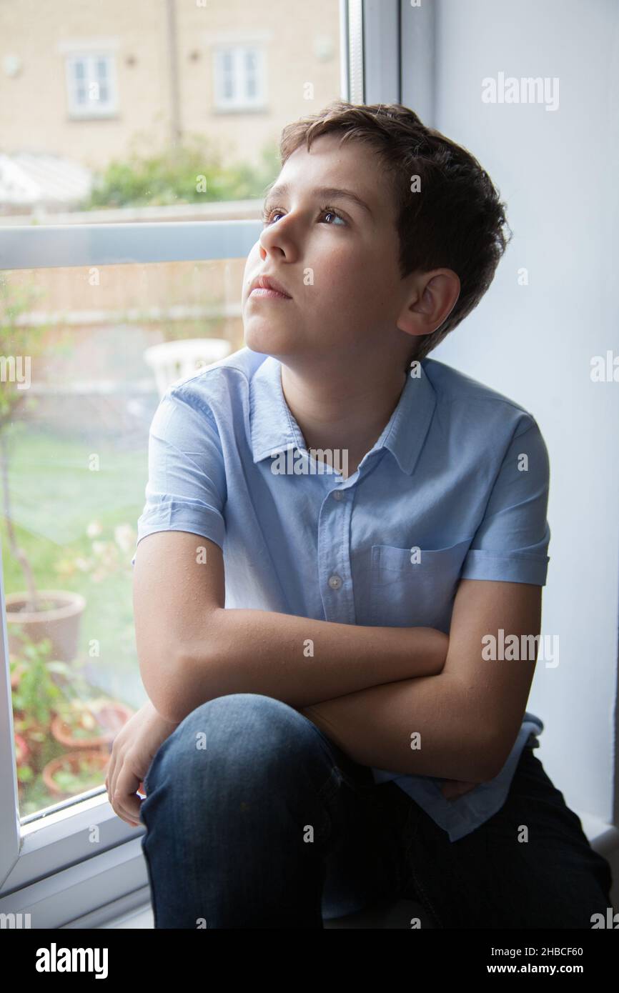 A boy sat in his windowsill in a thoughtful mood Stock Photo - Alamy