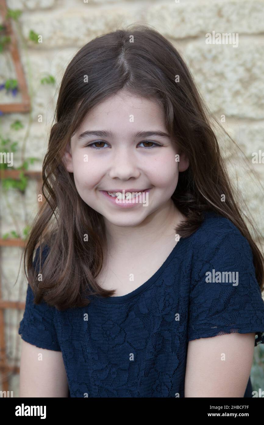 A portrait of a 7 year old girl stood against a stone wall Stock Photo ...