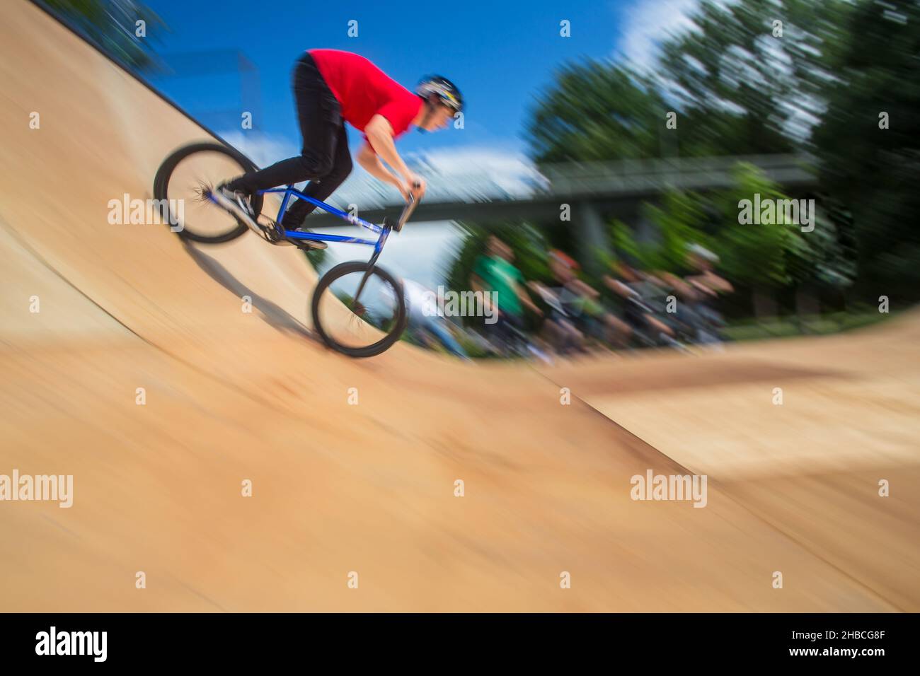 Bmx rider jumping over on a U ramp in a skatepark (motion blurred image ...