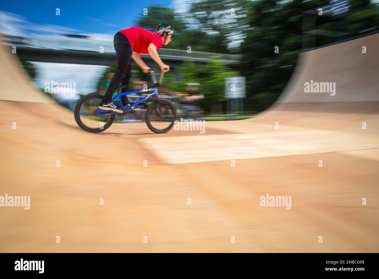 Bmx rider jumping over on a U ramp in a skatepark (motion blurred image ...