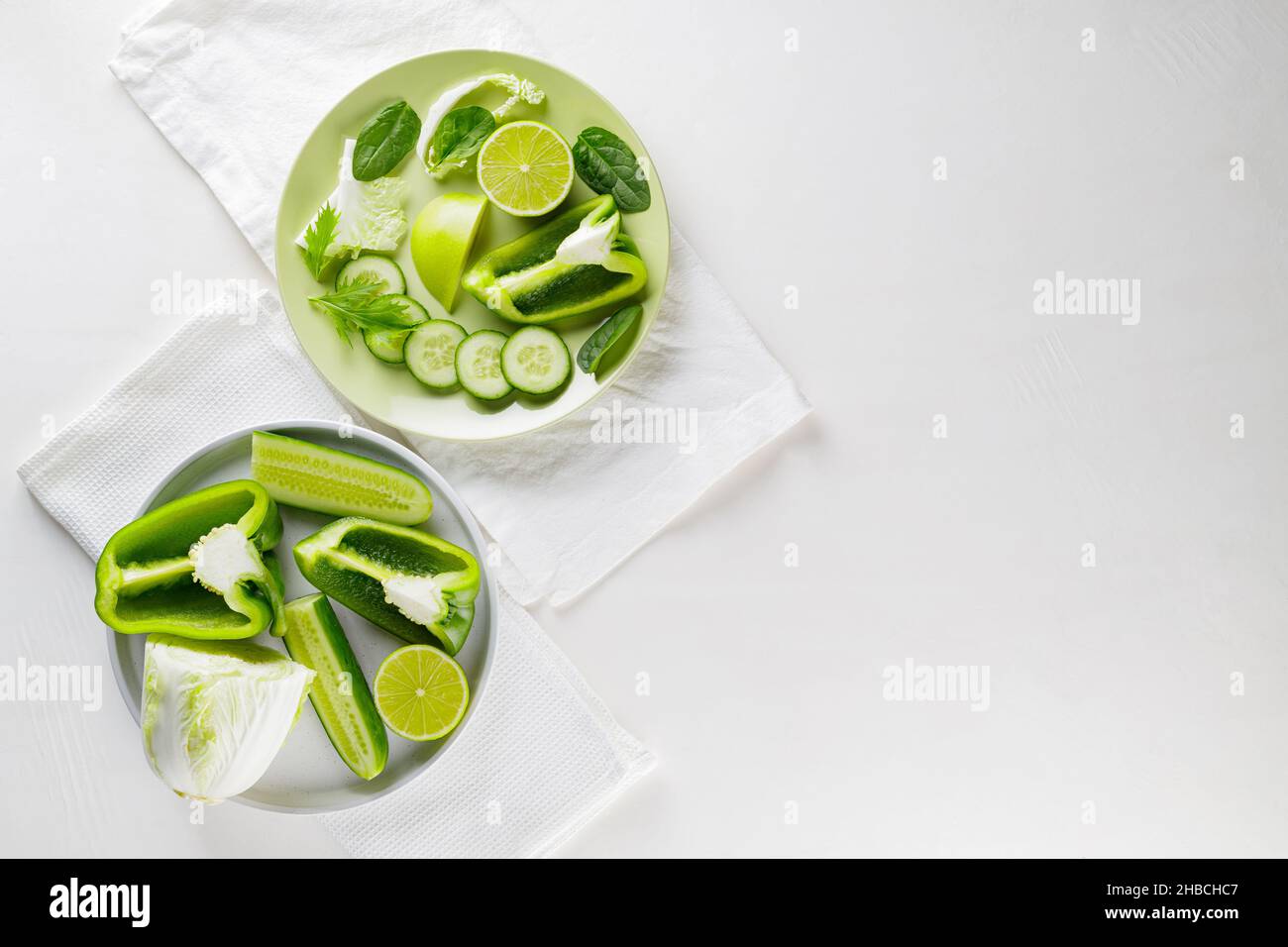 Sliced green vegetables and fruits on plates. Green diet food on white ...