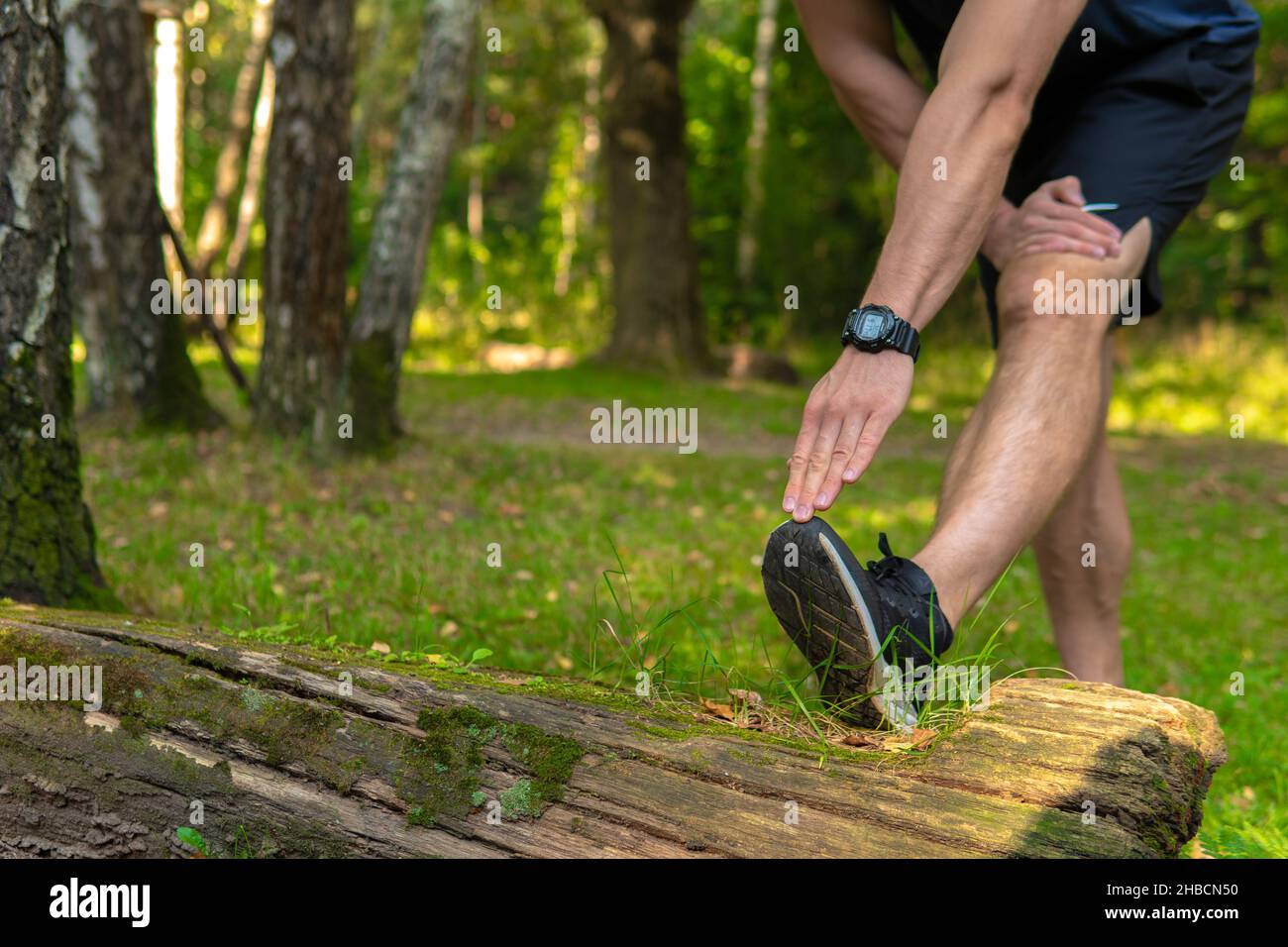 A young enduring athletic athlete is doing stretching in the forest ...