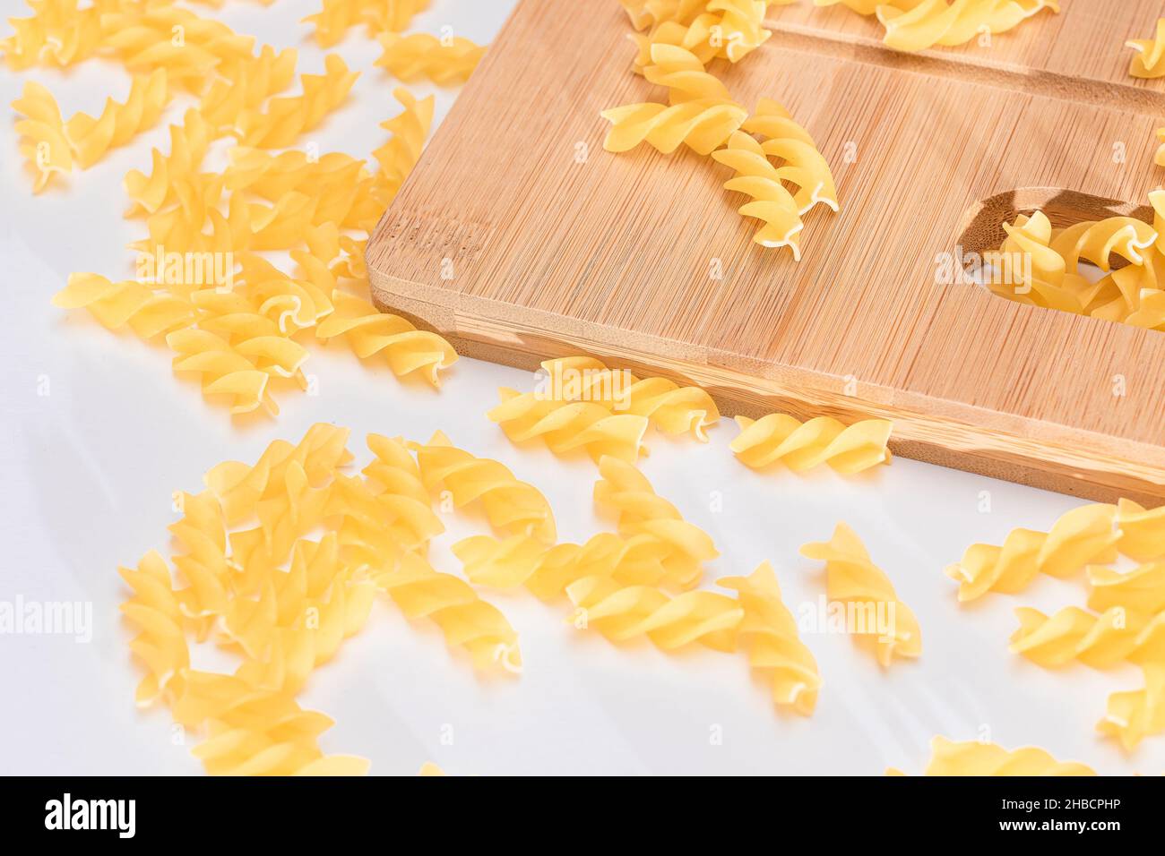 Uncooked Fusilli Pasta Scattered on Wooden Board and White Table. Raw ...