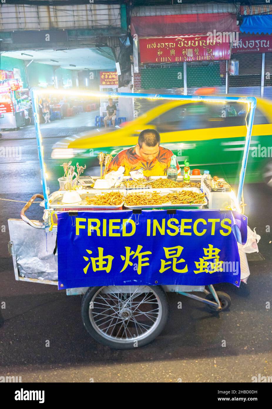 A street vendor at the wheeled stall selling fried insects to tourists ...