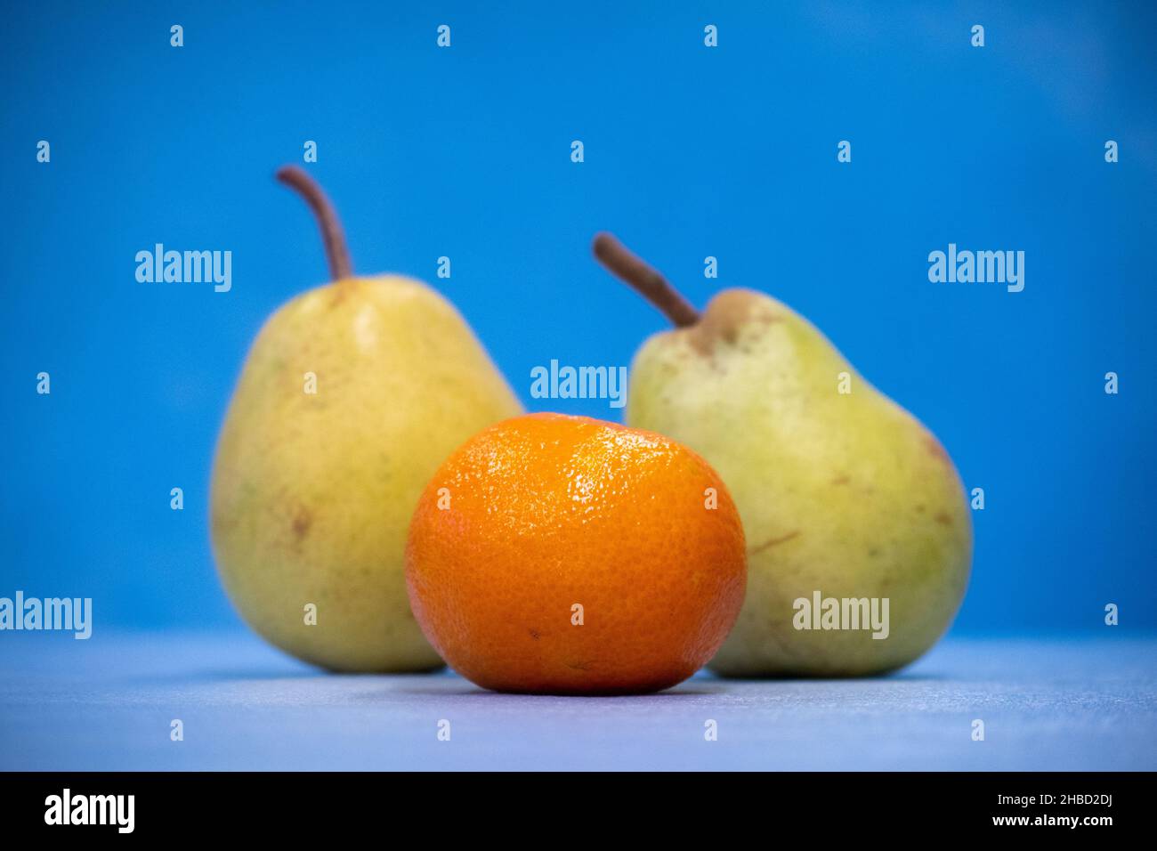 a close up of a bitten pear is standing and the background is blue ...