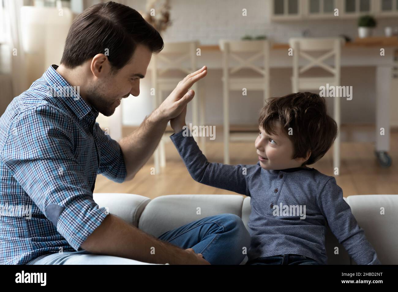 Overjoyed father and little son giving high five, celebrating success ...